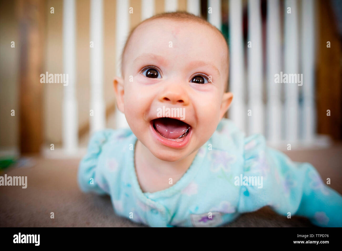 Cheerful baby girl lying on rug at home Stock Photo - Alamy