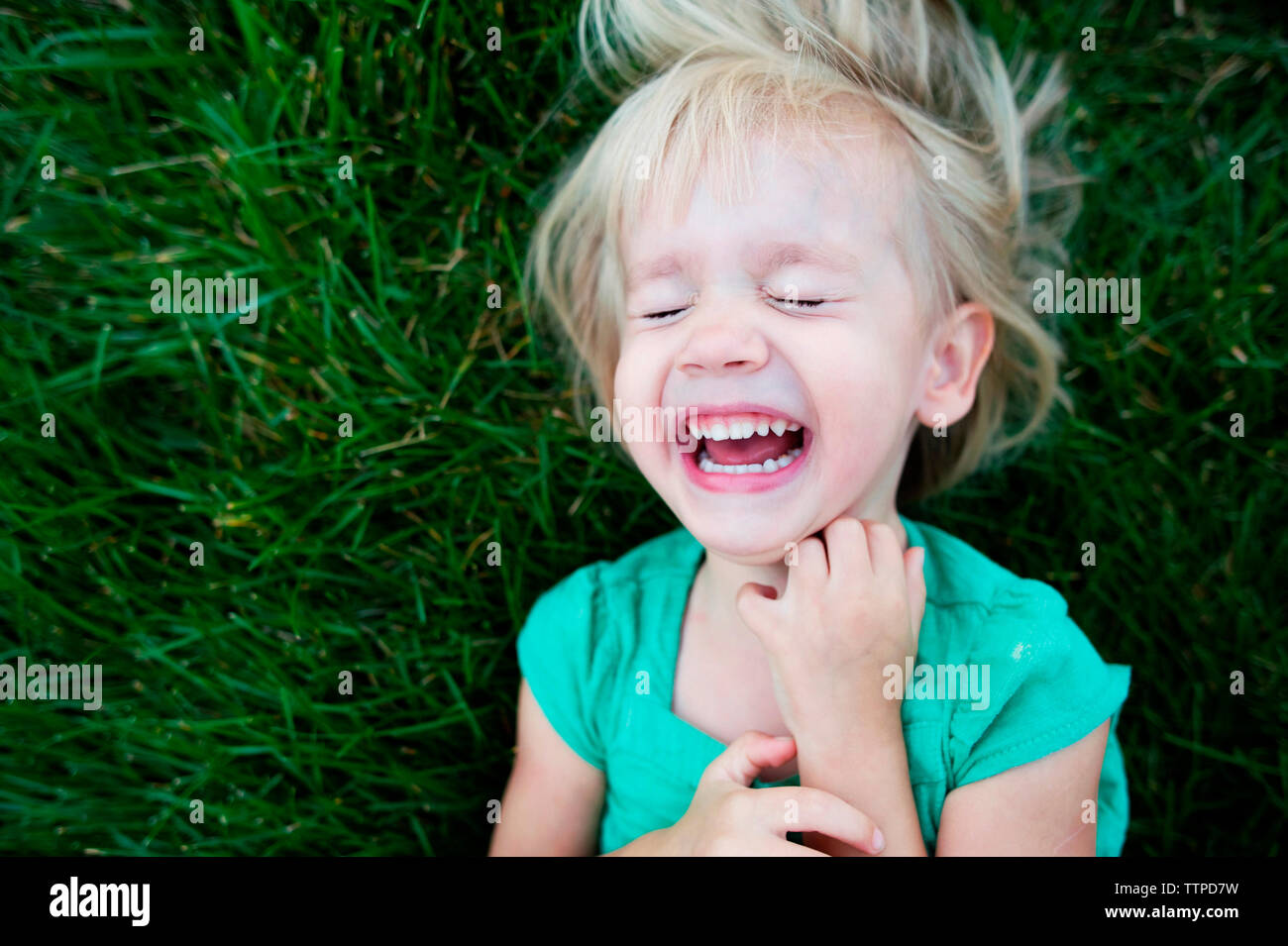 Overhead view of girl crying while lying on grassy field at park Stock ...