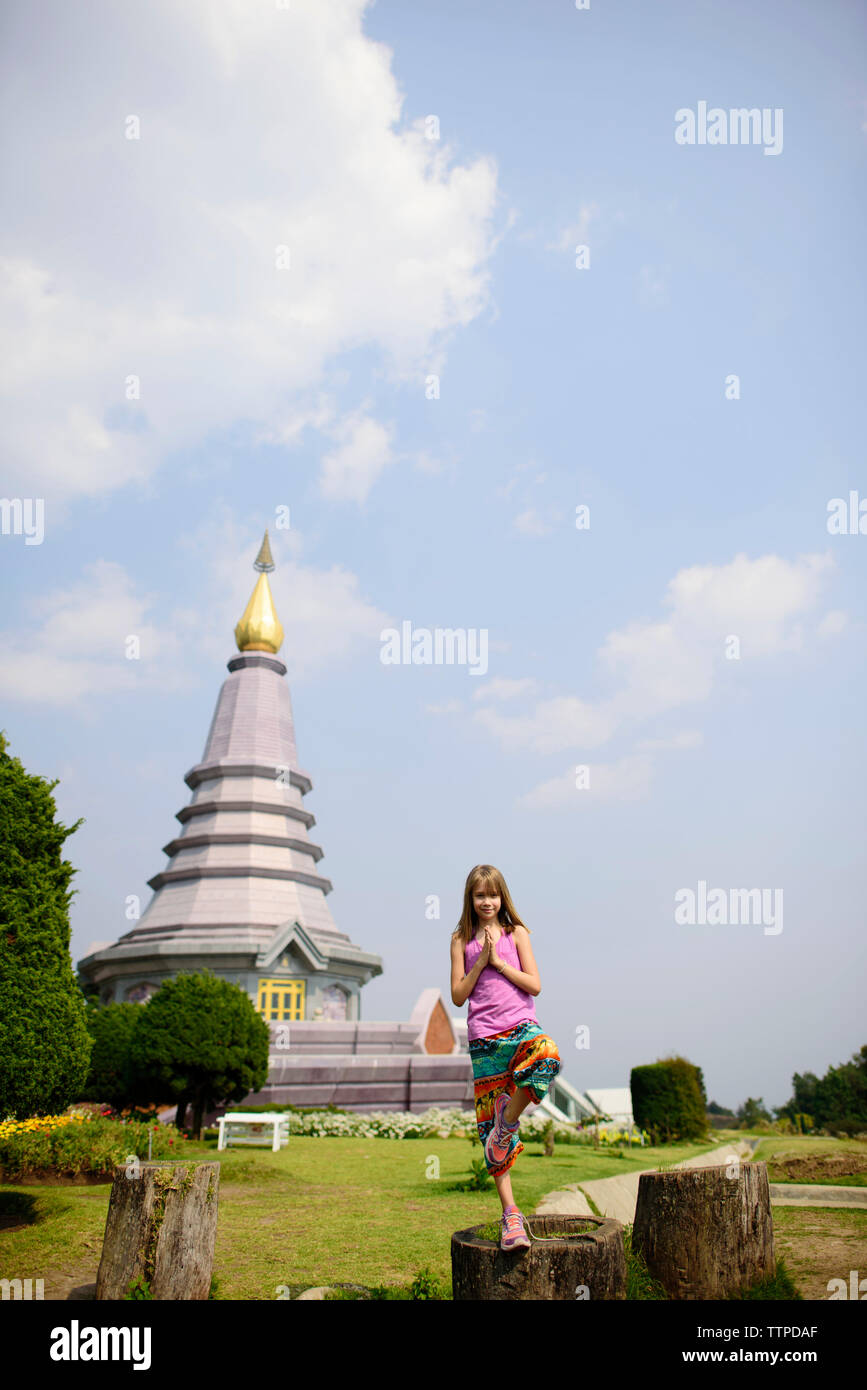 Girl standing in tree pose against pagoda at Doi Inthanon National Park ...