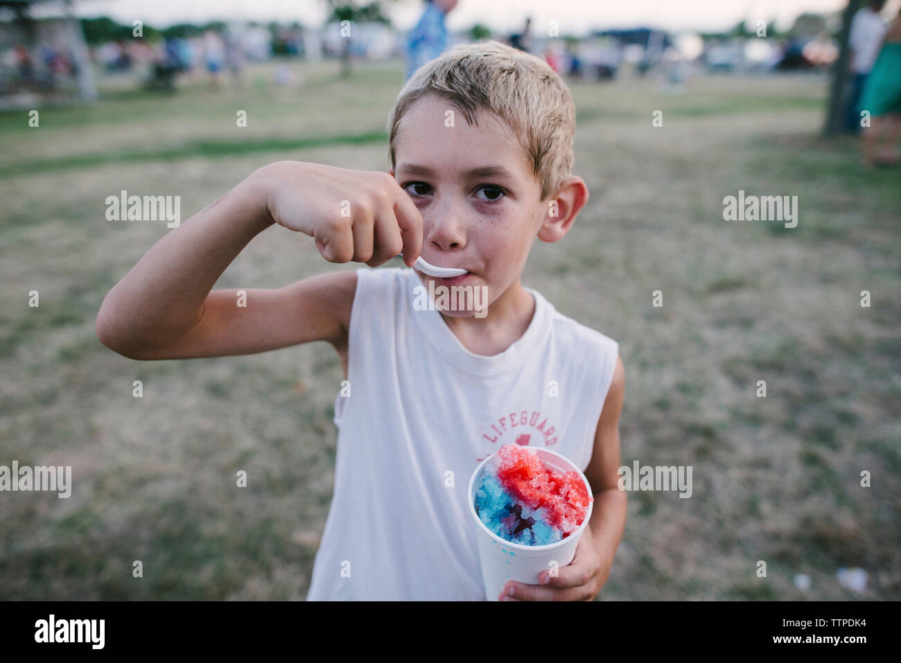 Portrait of boy eating crushed ice at field Stock Photo - Alamy