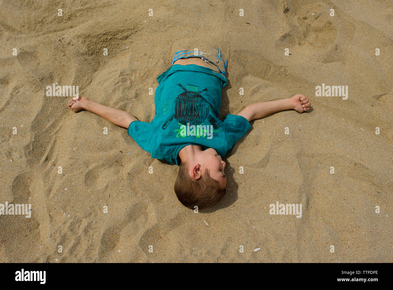 High angle view of boy buried in sand at beach Stock Photo - Alamy
