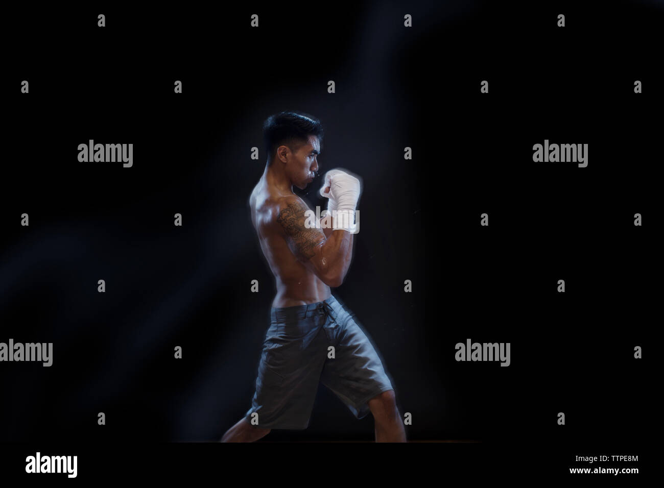 Side view of male kickboxer fighting against black background Stock ...