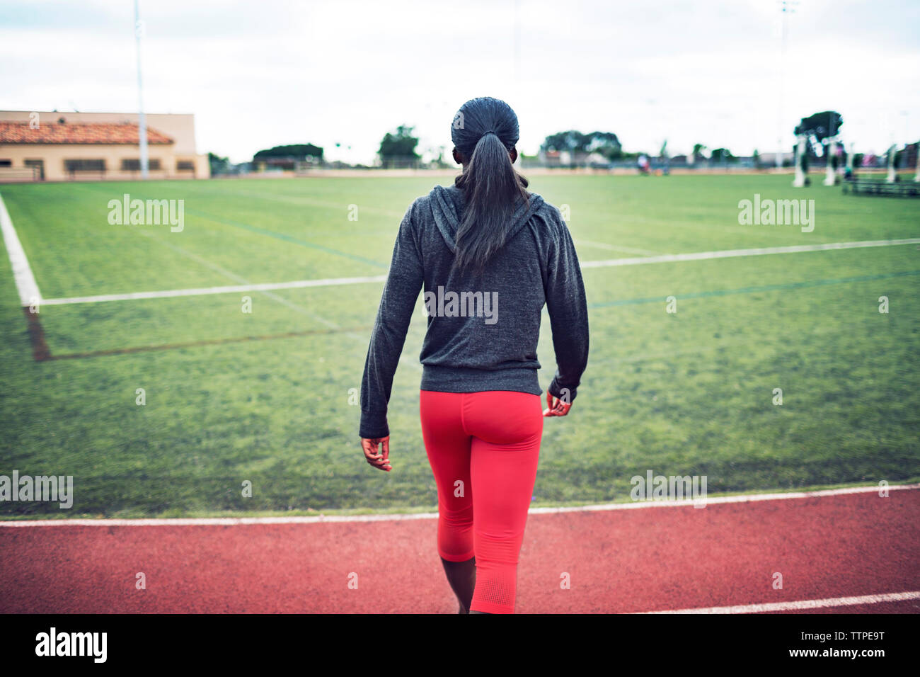 Rear view of sporty woman walking on field Stock Photo - Alamy