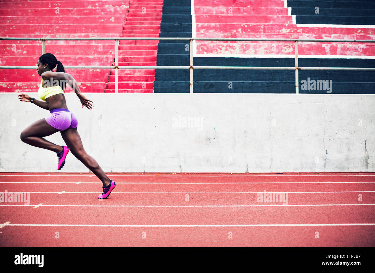 Side view of determined female athlete running on tracks Stock Photo ...
