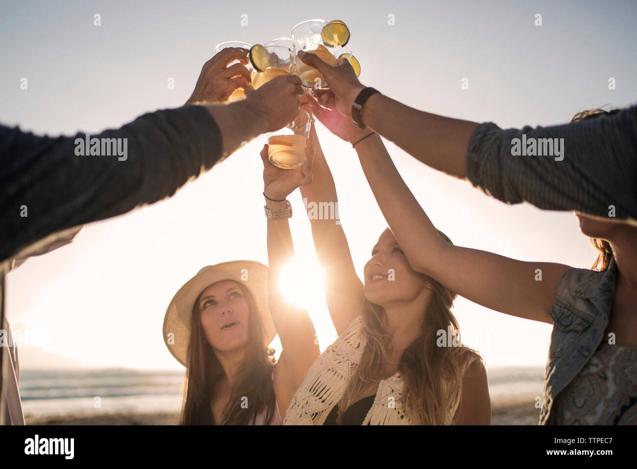 Happy friends toasting drinks on beach Stock Photo - Alamy