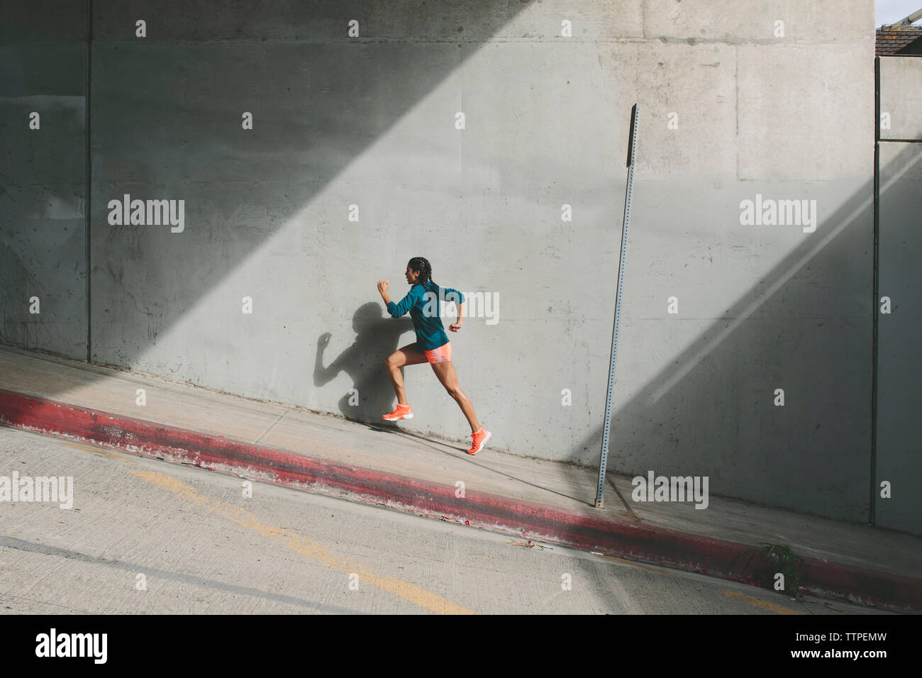 Side view of young woman running on road Stock Photo - Alamy