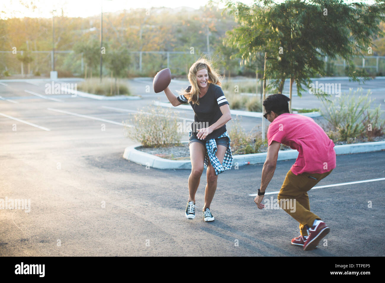 Happy friends playing with American football at parking lot Stock Photo ...