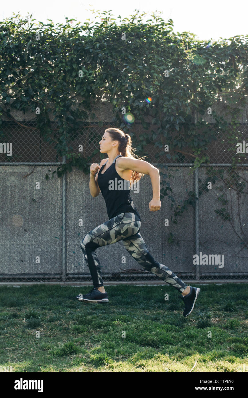 Full length side view of determined female athlete running at park ...