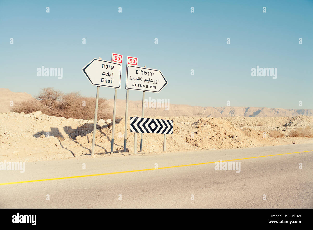 Sign boards on road at desert against clear sky Stock Photo - Alamy