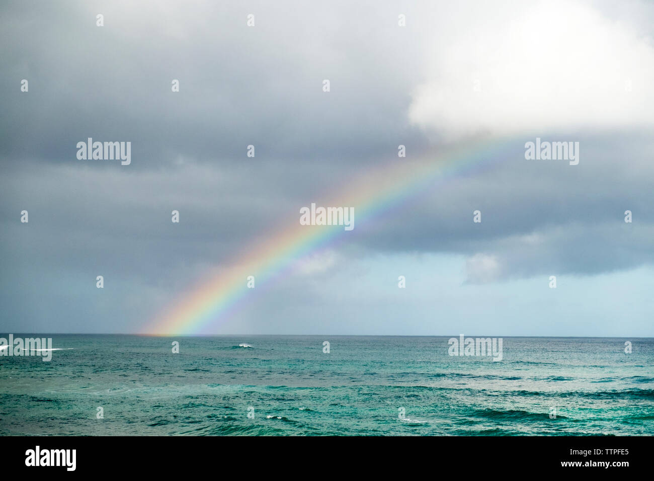 Idyllic view of rainbow over sea against cloudy sky Stock Photo - Alamy
