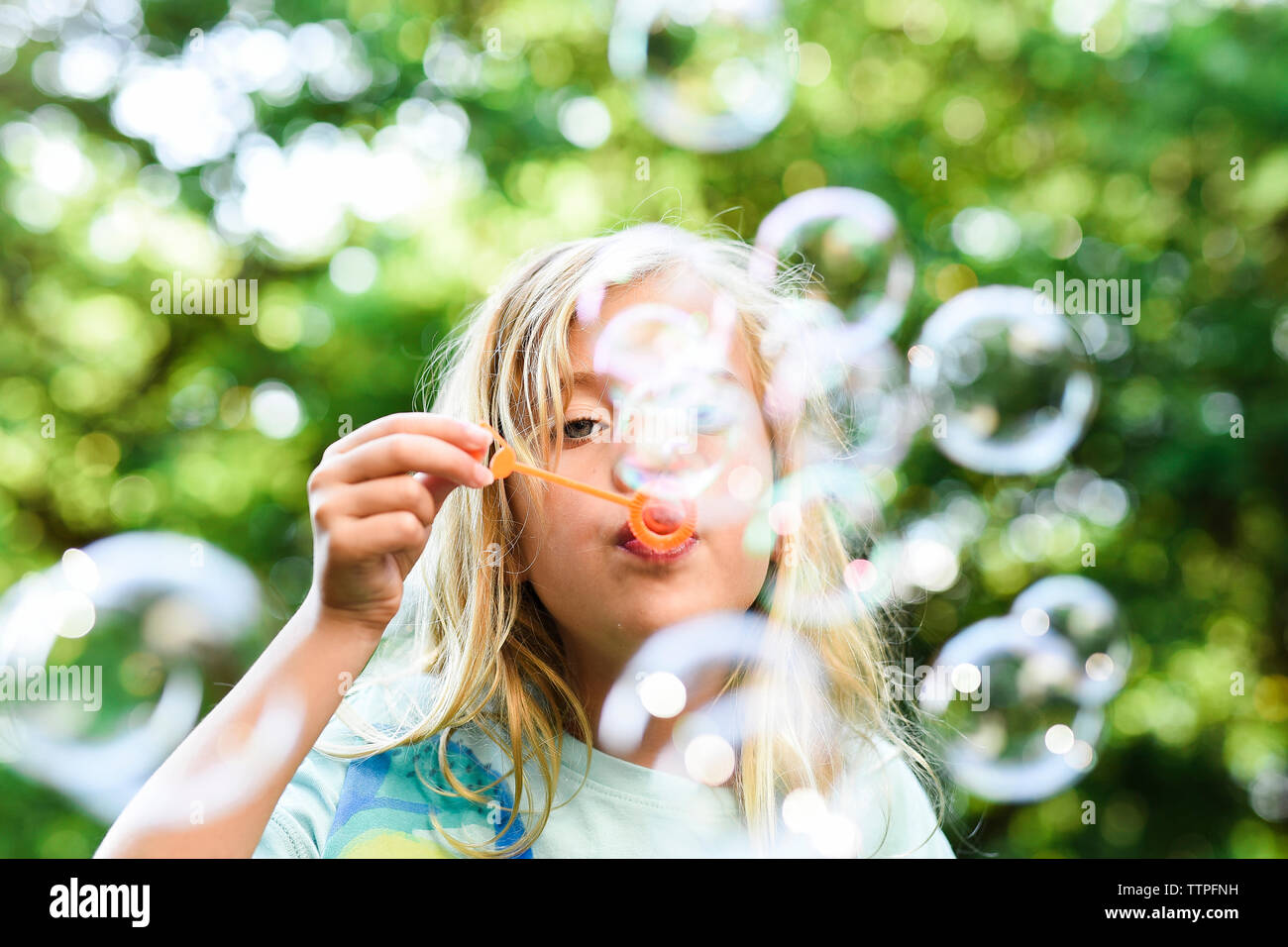 Girl blowing bubbles at park Stock Photo - Alamy