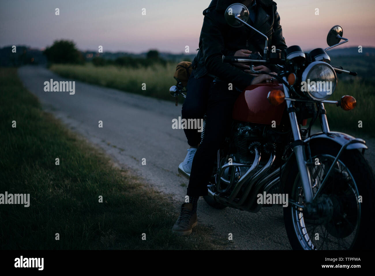 Low section of couple sitting on motorcycle Stock Photo - Alamy