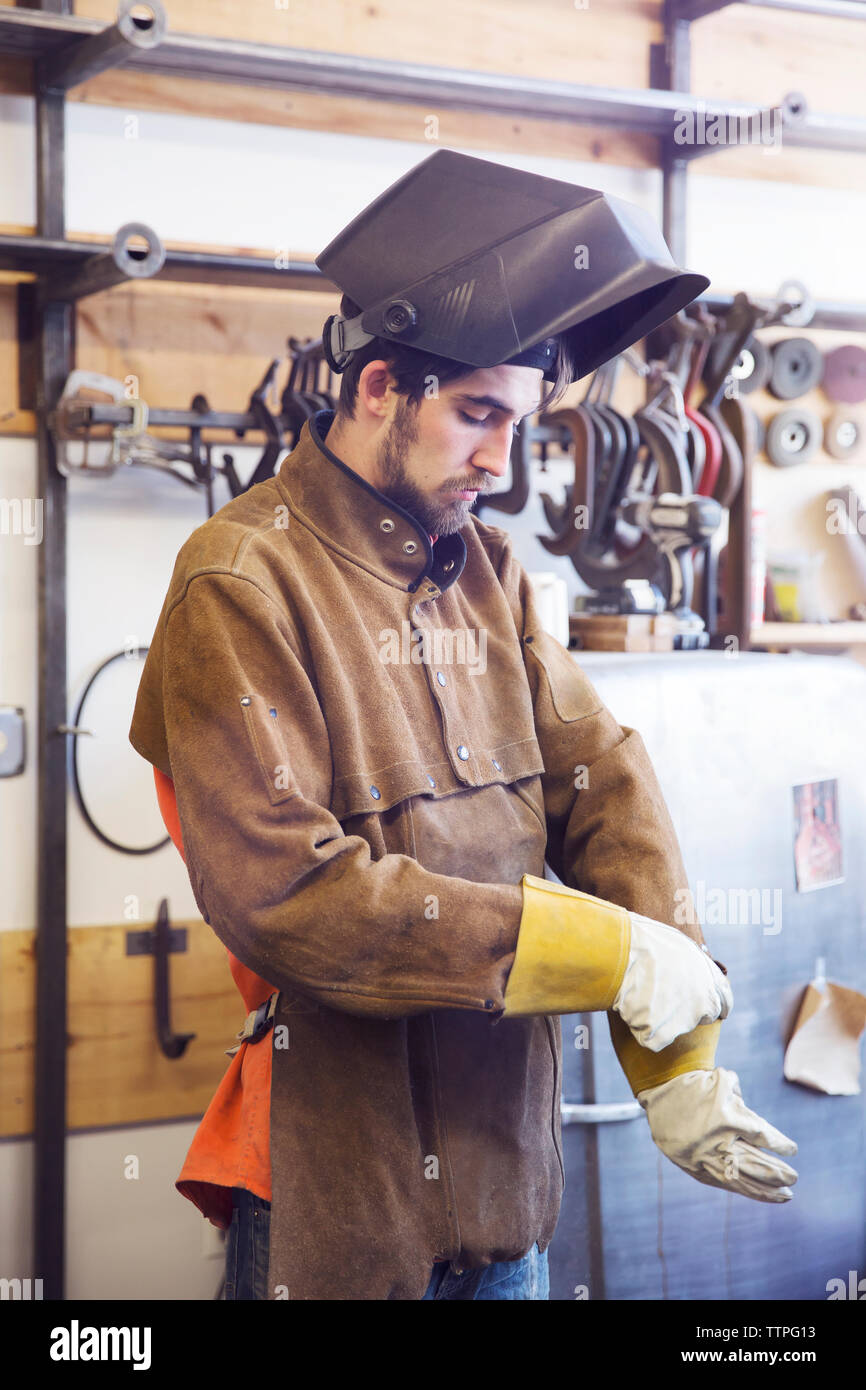 Male craftsperson wearing gloves at workshop Stock Photo - Alamy