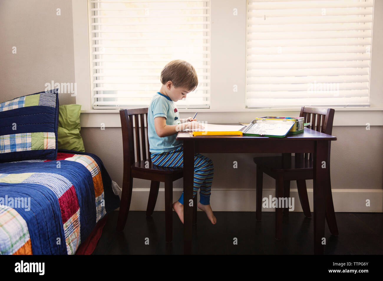 Boy studying on table in bedroom against window Stock Photo - Alamy