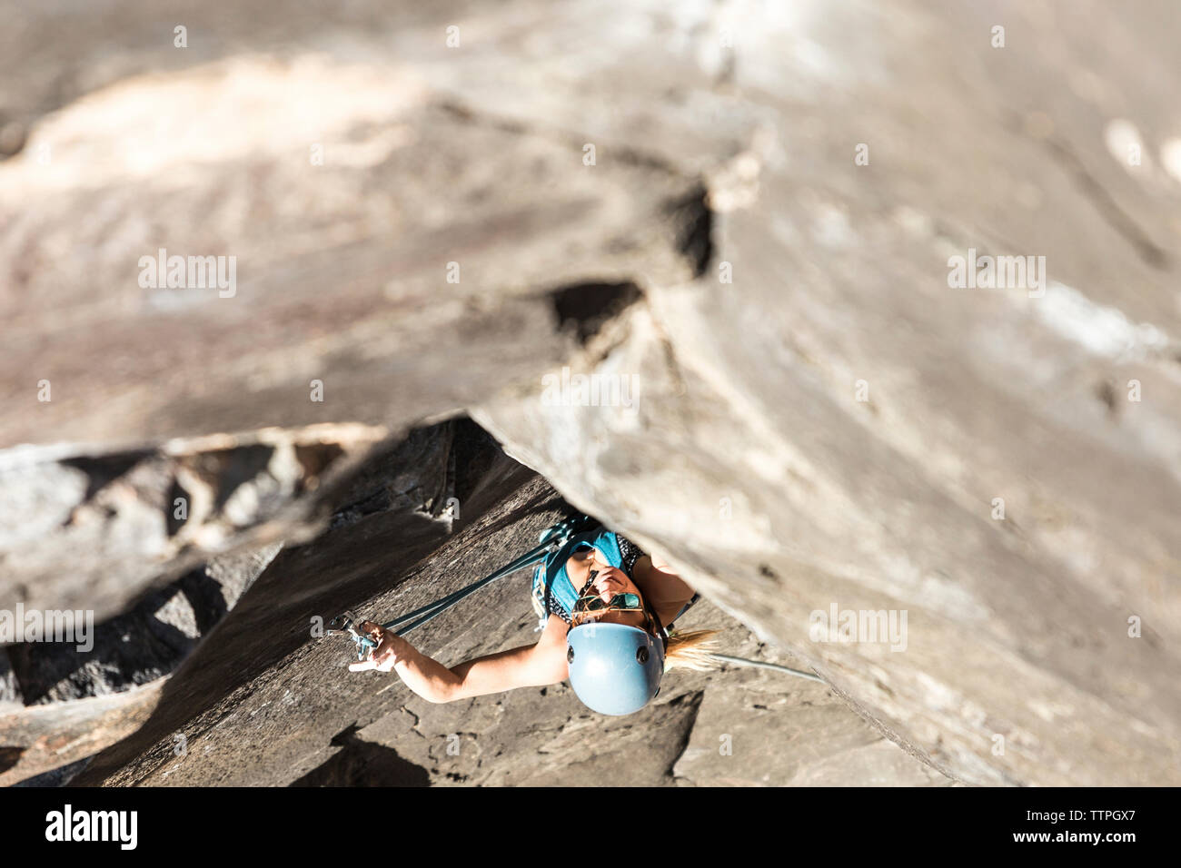 High angle view of female hiker wearing helmet while climbing on ...
