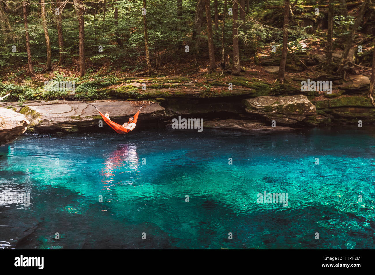 Man rests in hammock over beautiful, blue spring in upstate New York ...