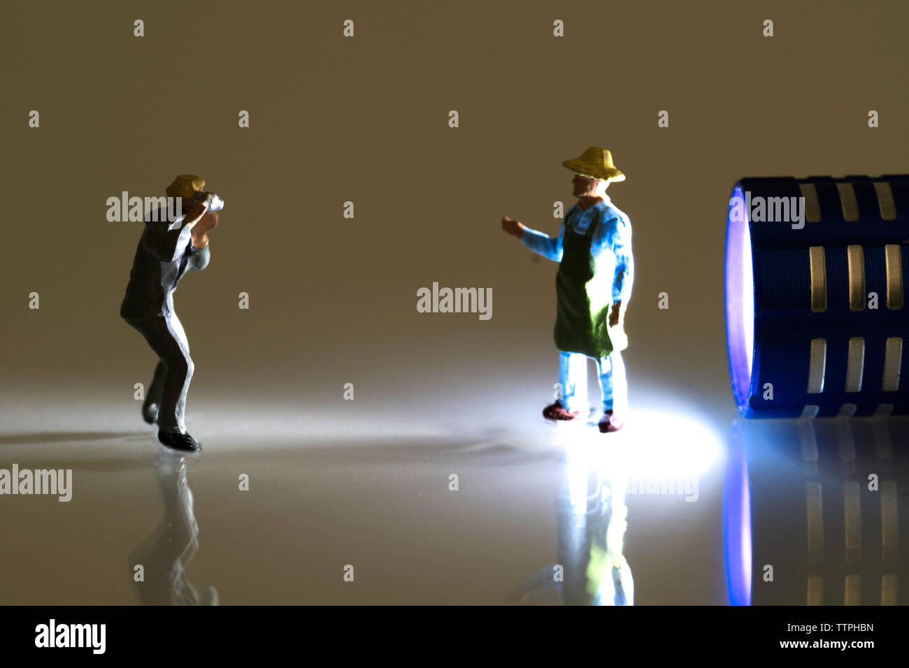 Miniature Photographer taking pictures of a backlit man with apron ...