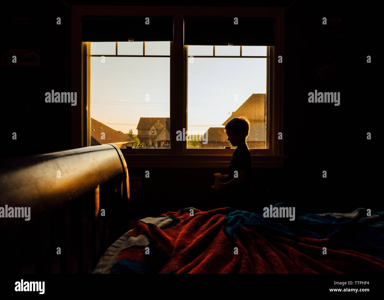 Boy standing by window in dark room Stock Photo - Alamy