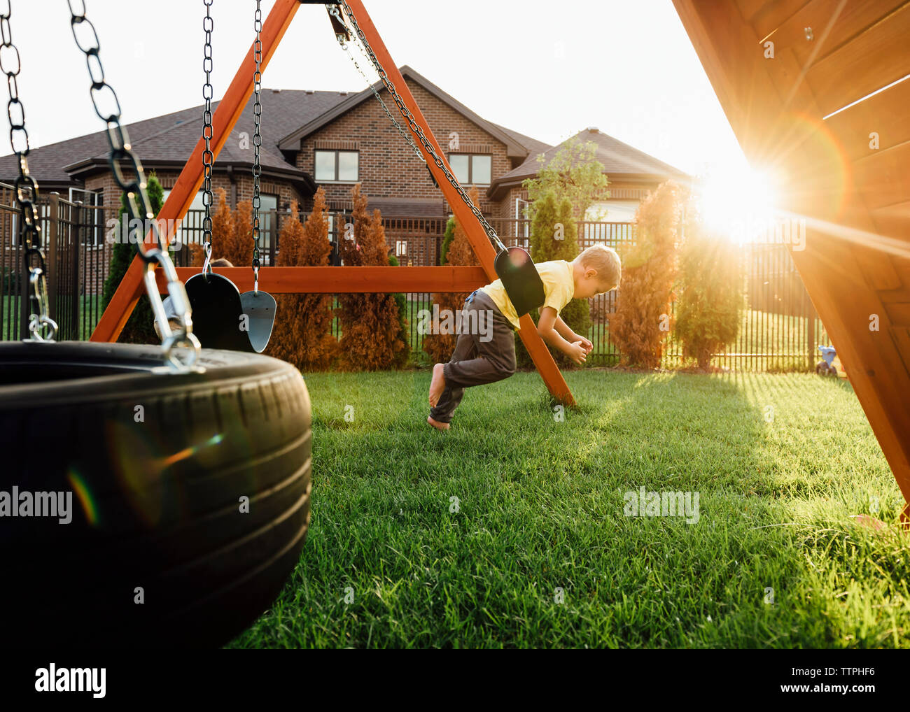 Boy playing on swing at yard Stock Photo - Alamy