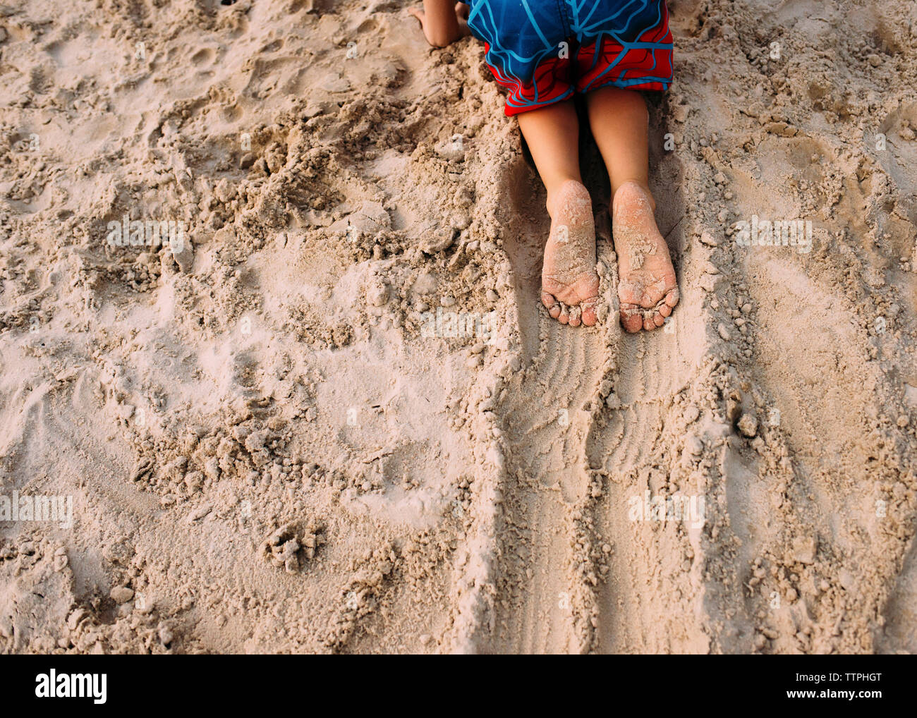 Cropped image of boy crawling in sand Stock Photo - Alamy