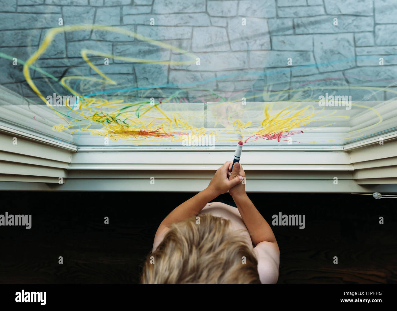 Boy drawing with crayon on window at home Stock Photo - Alamy