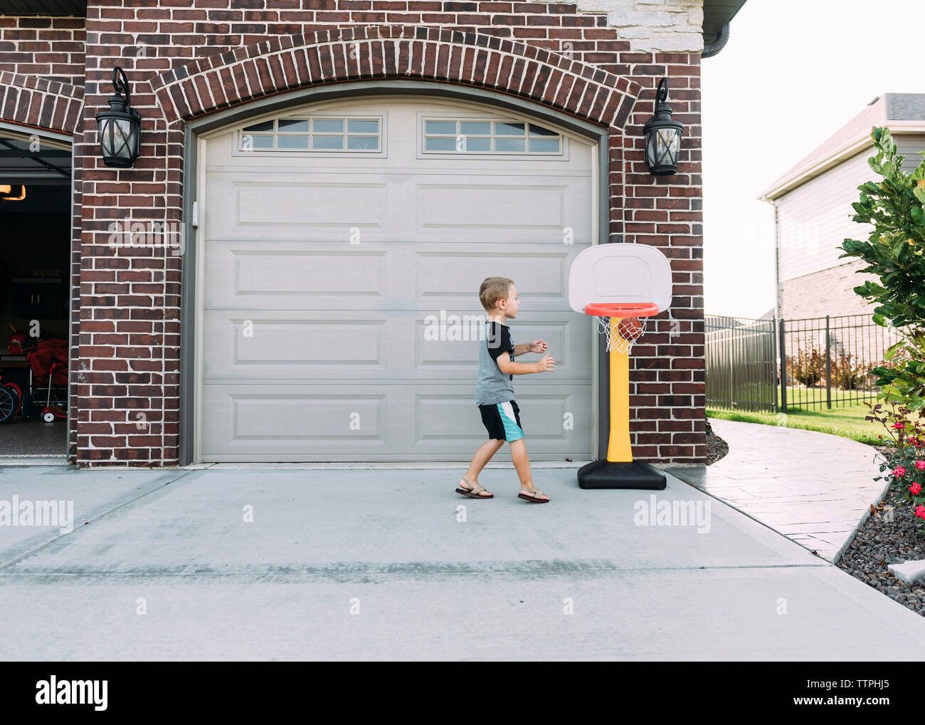 Happy boy playing basketball on driveway Stock Photo - Alamy