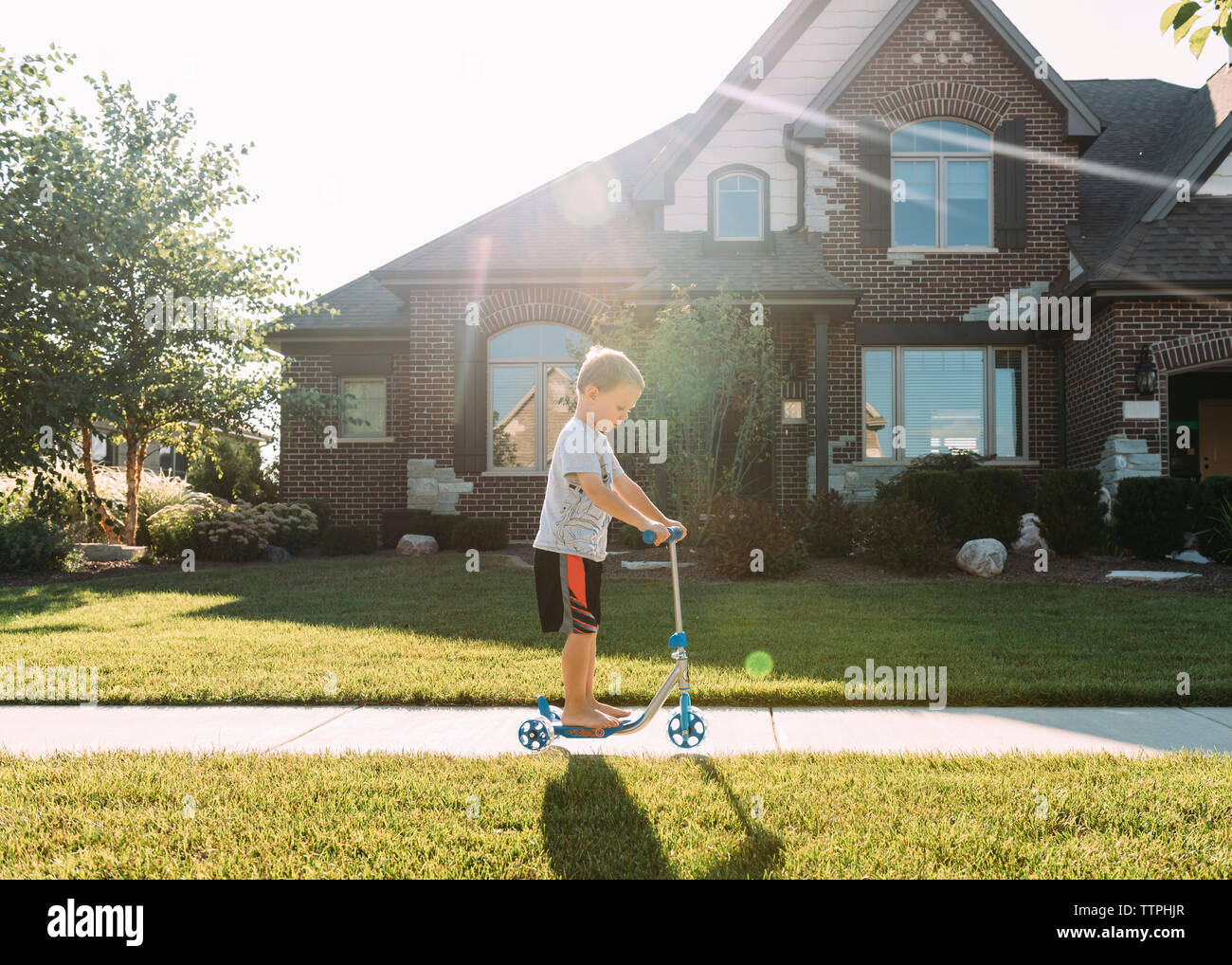 Cute boy standing with his push scooter outdoors Stock Photo - Alamy