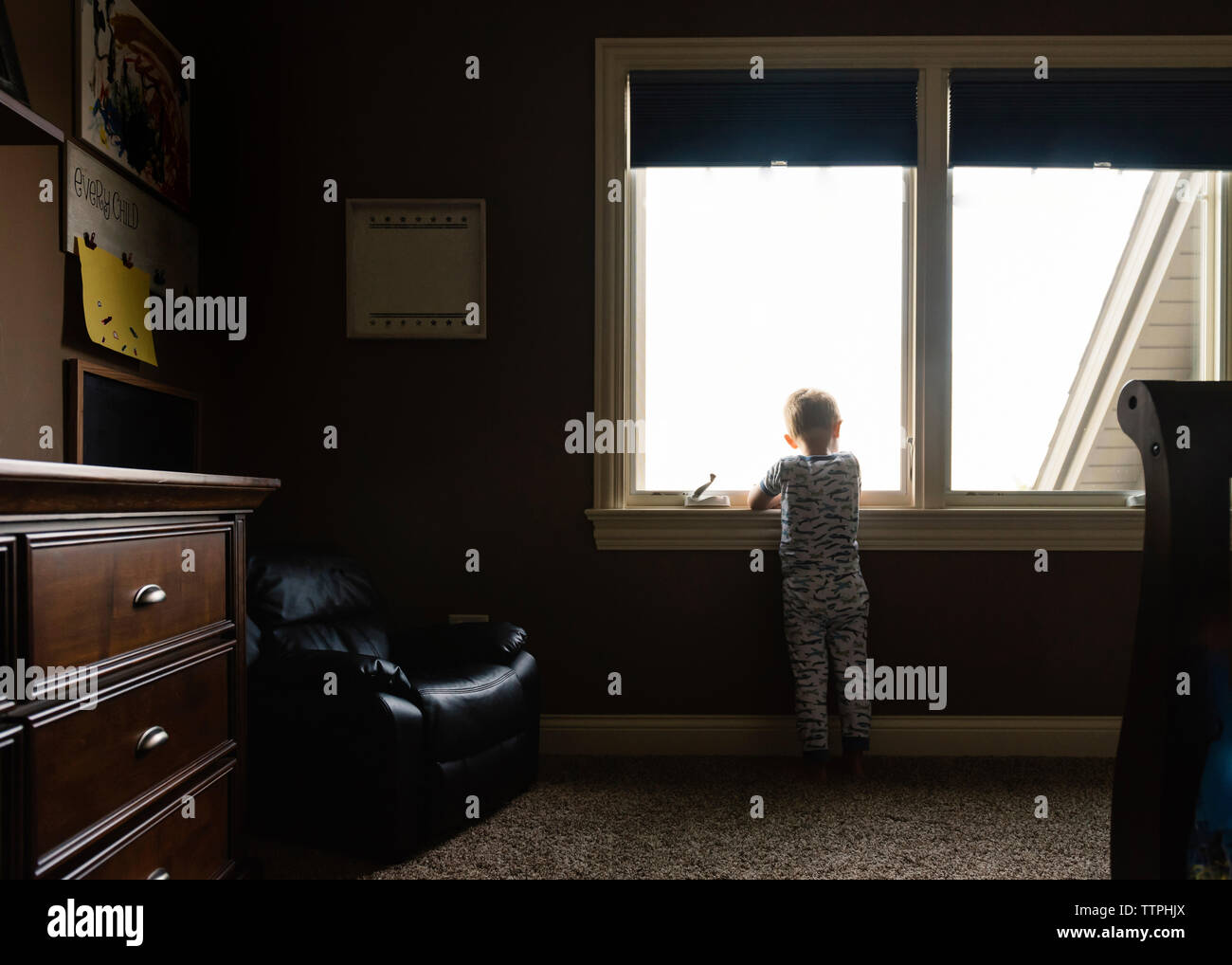 Rear view of boy looking through window Stock Photo - Alamy