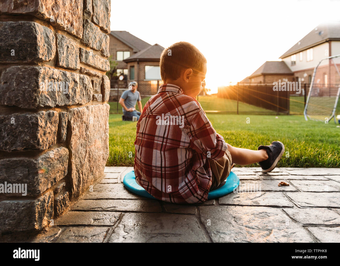 Boy sitting by column with father in background Stock Photo - Alamy