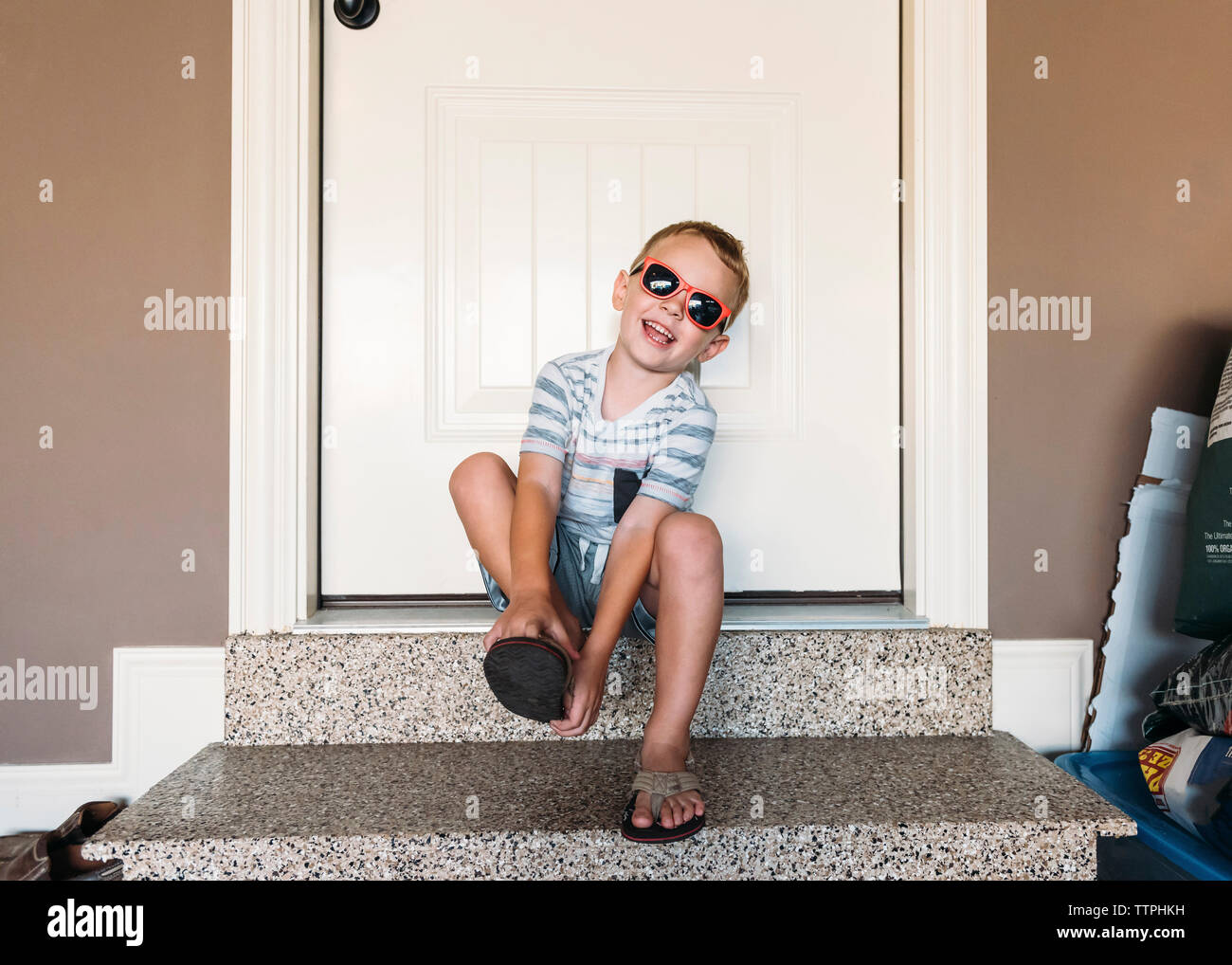 Boy wearing slippers while sitting on doorway Stock Photo - Alamy