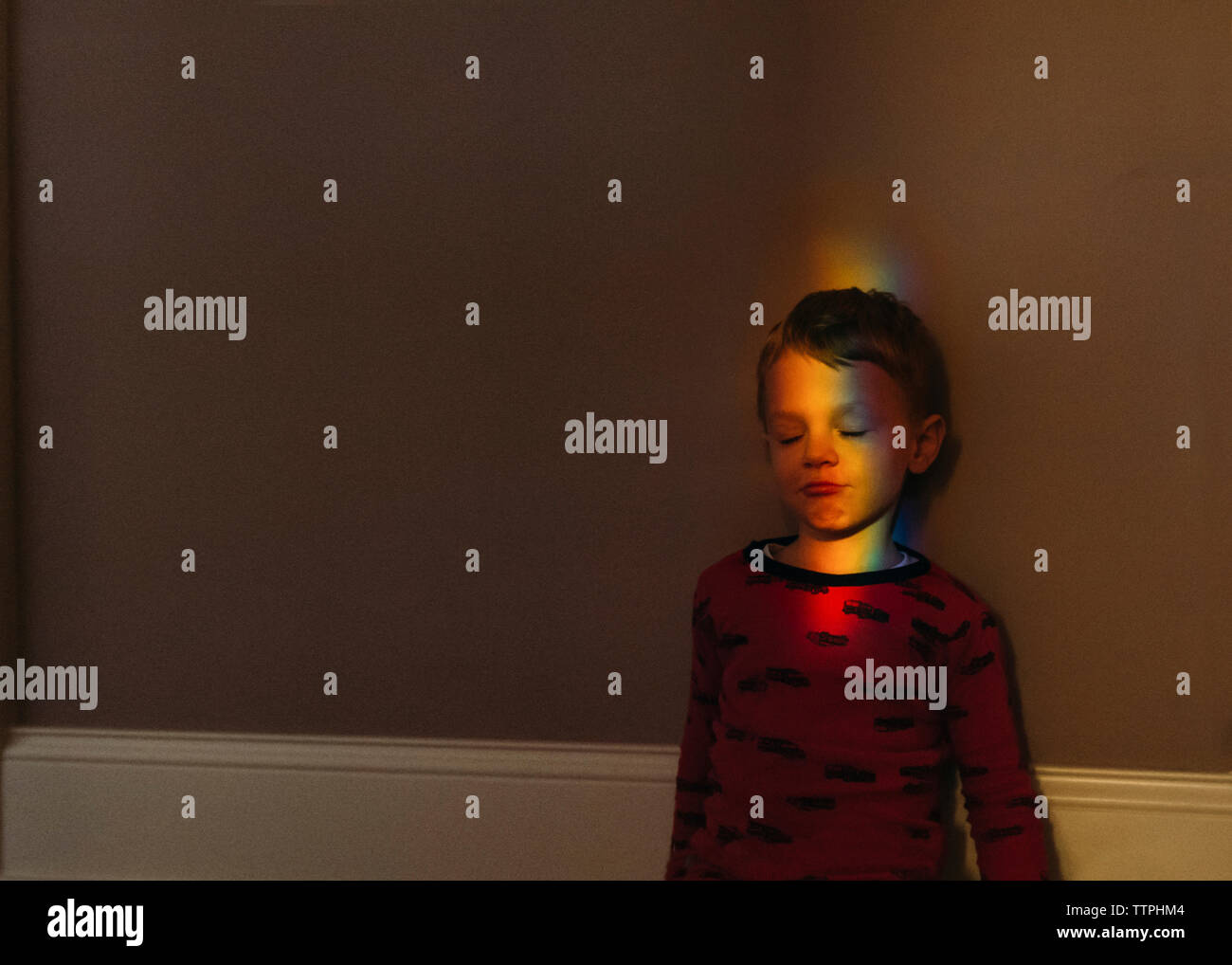 Sunlight falling on boy with eyes closed standing by wall at home Stock ...