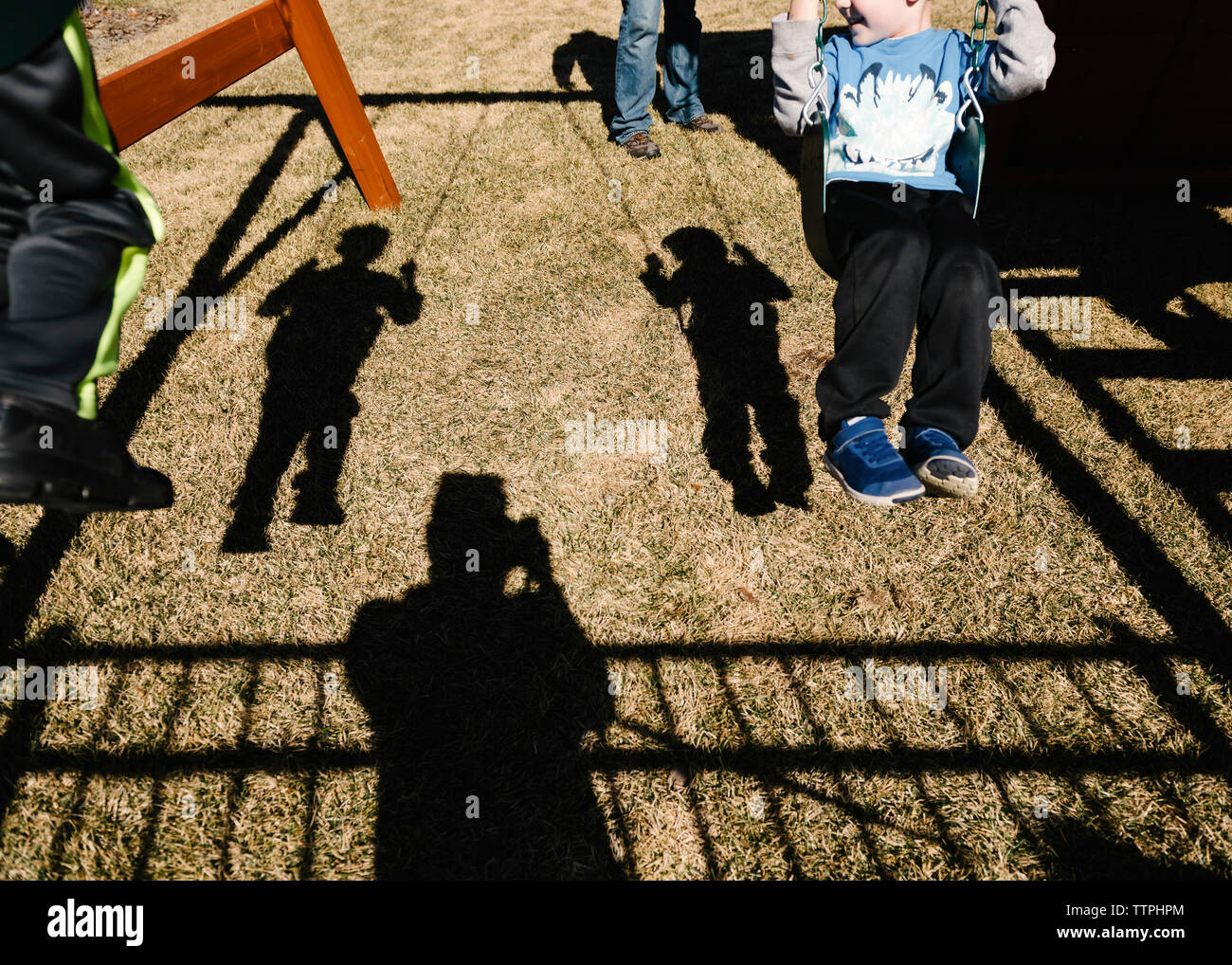 Shadow of sons swinging while father standing at playground Stock Photo ...