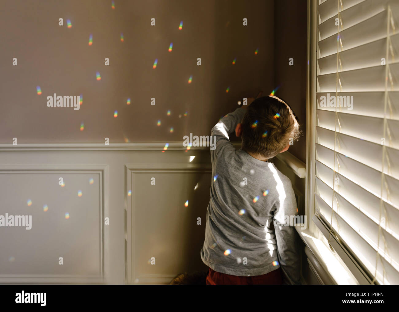 Boy playing with spectrum while standing by window Stock Photo - Alamy