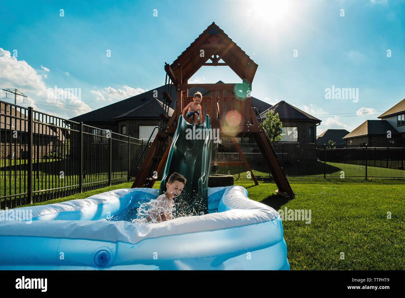 Brothers sliding into wading pool against sky at park Stock Photo - Alamy