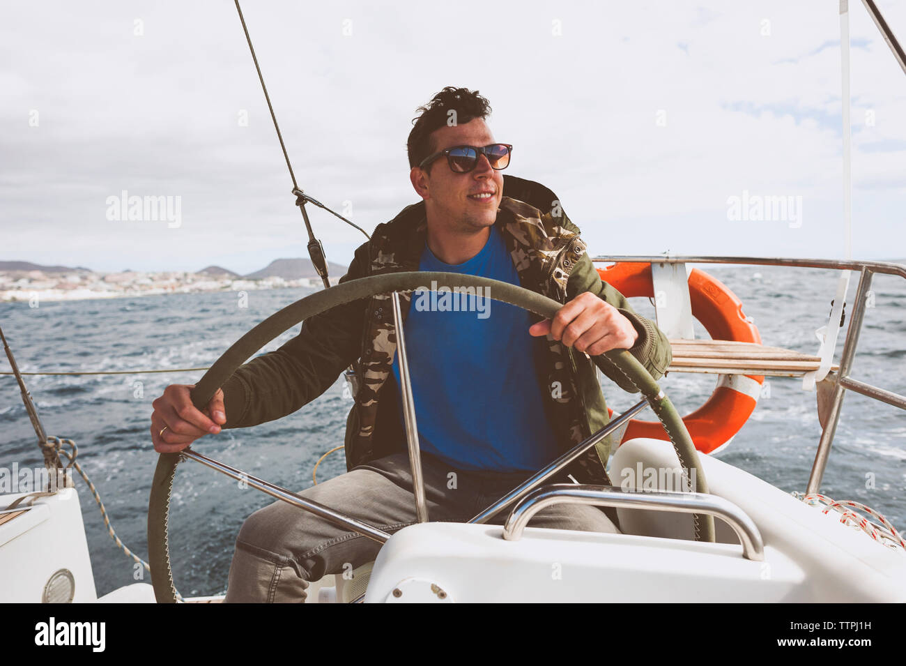 Happy man driving nautical vessel on sea against cloudy sky Stock Photo ...