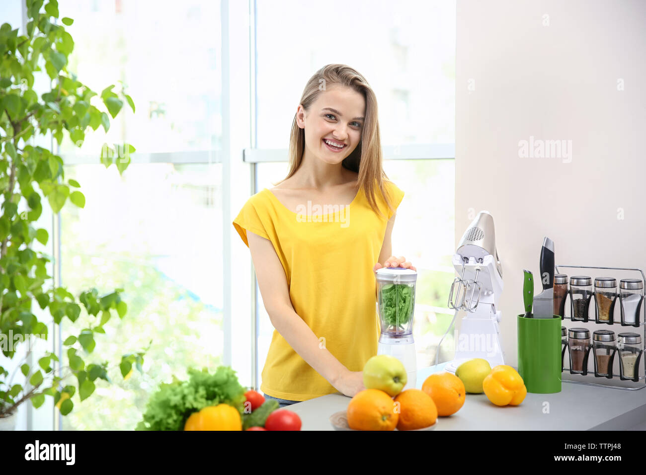 Young beautiful woman making fresh juice in kitchen Stock Photo - Alamy