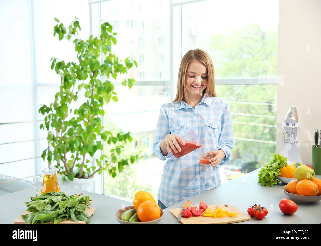 Young woman making fresh juice in the kitchen Stock Photo - Alamy