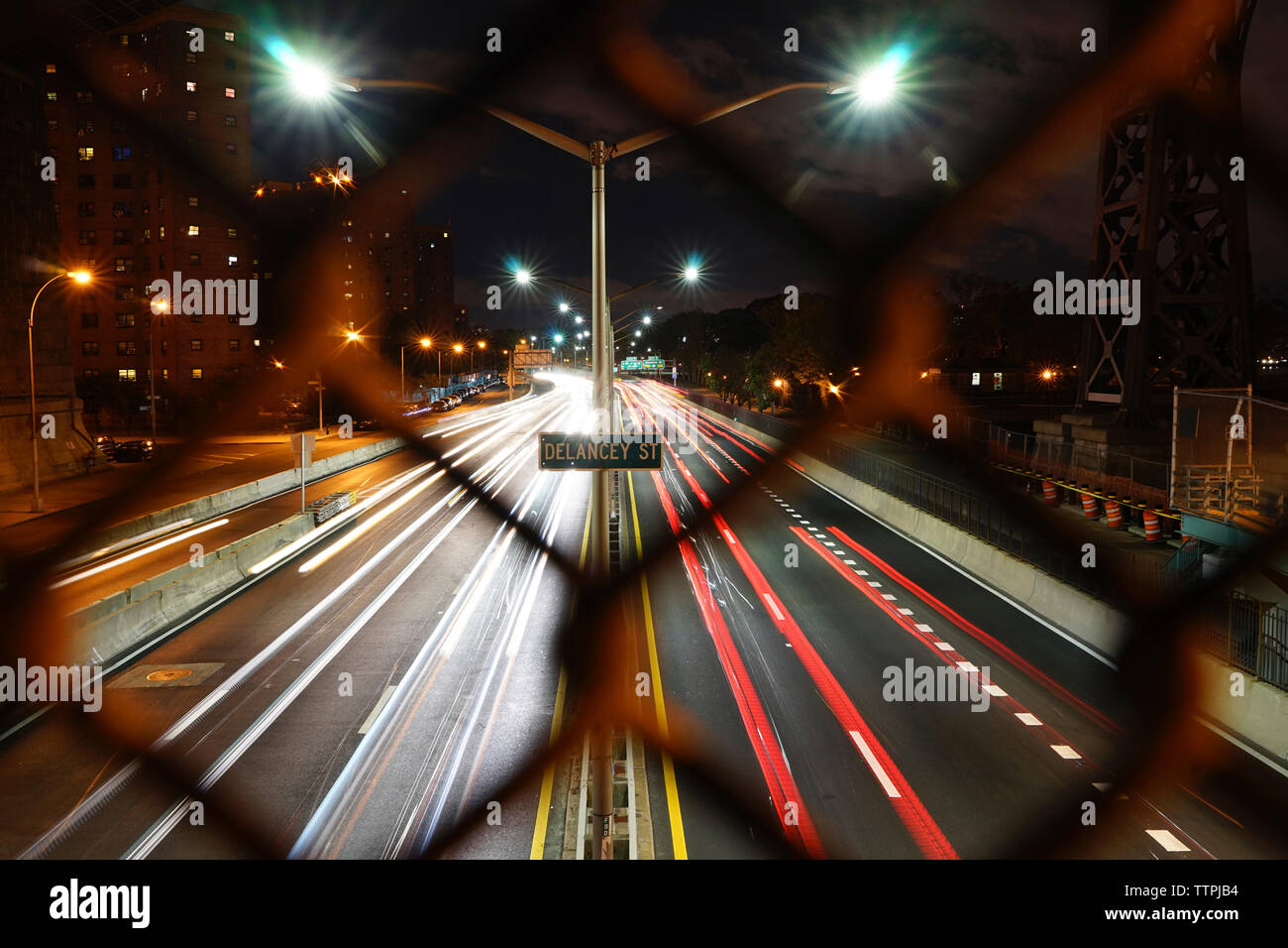 Light trails on city street seen through fence Stock Photo - Alamy