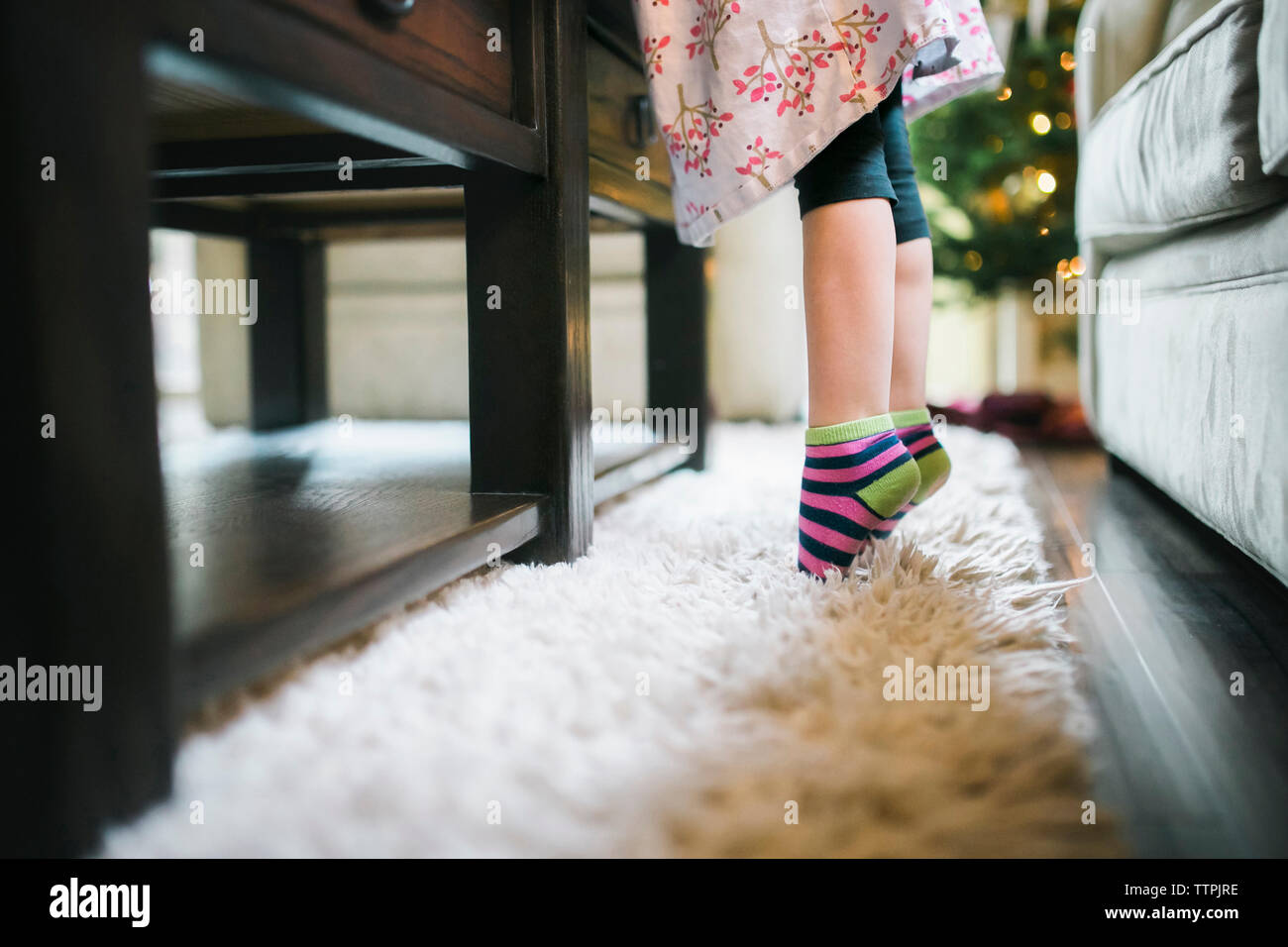 Low section of girl tiptoeing on rug by table at home Stock Photo - Alamy