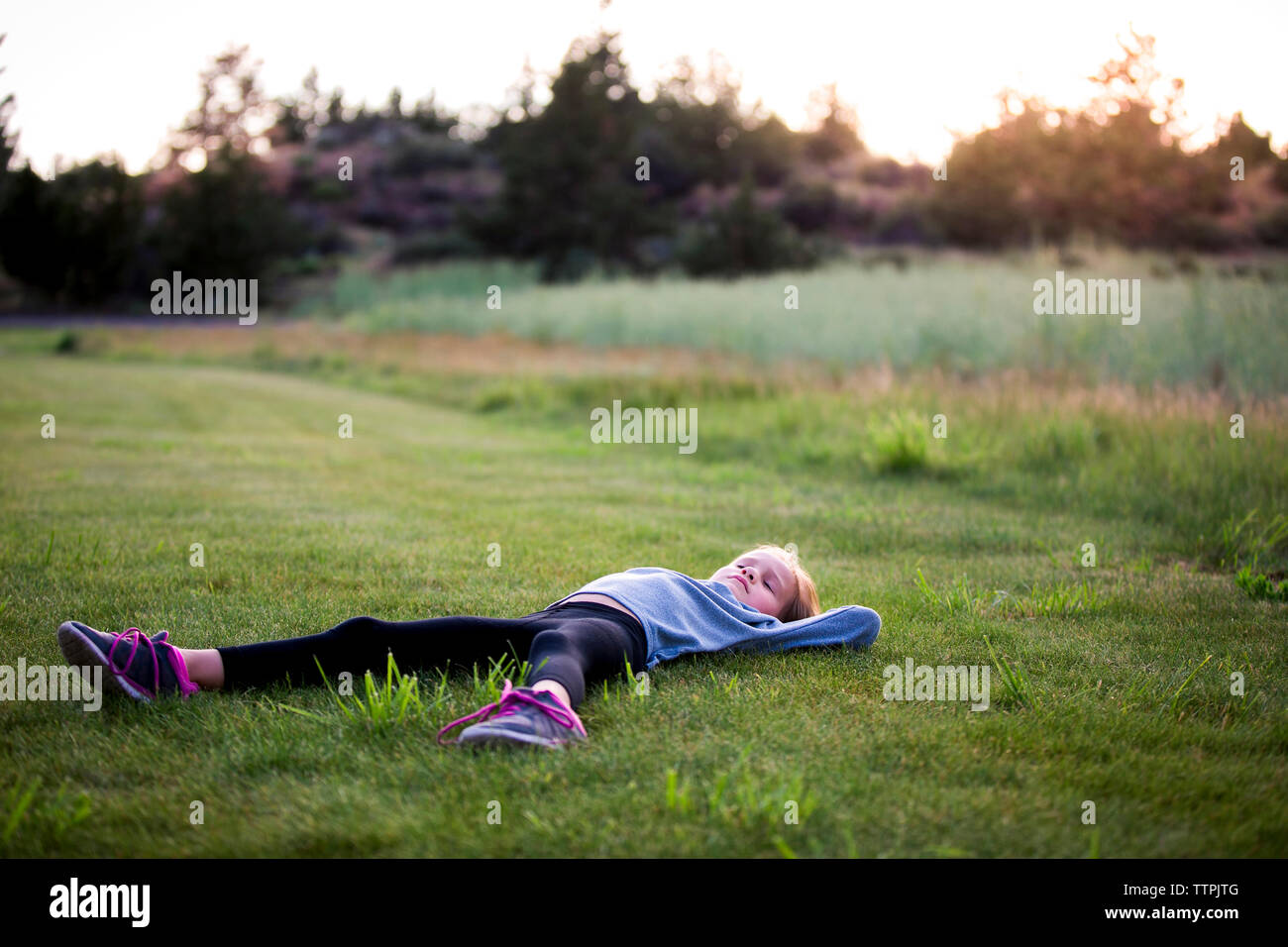 Girl lying on grassy field Stock Photo - Alamy
