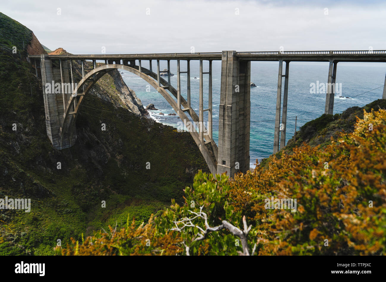 Arch bridge over mountains by sea Stock Photo - Alamy