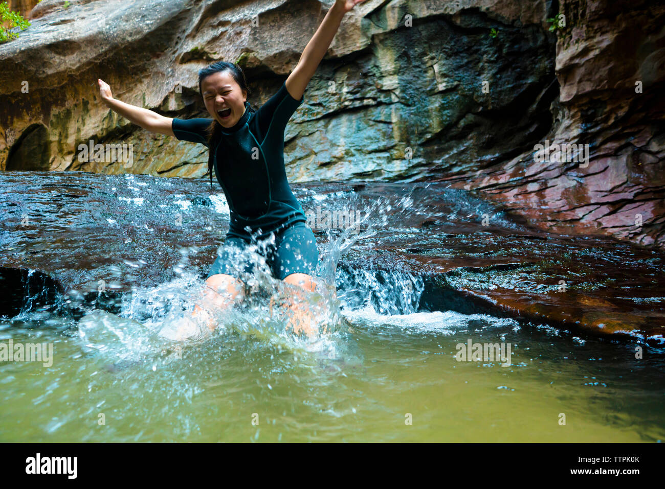 Cheerful woman jumping in pond by rock formation Stock Photo - Alamy