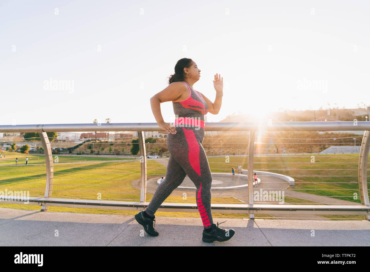 Side view of woman jogging on elevated walkway against clear sky Stock ...