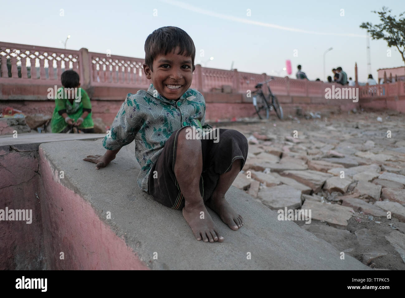 Full length portrait of smiling messy boy playing on retaining wall in ...