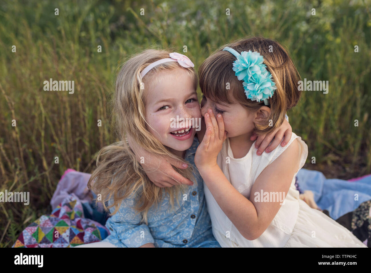 two smiling girls whispering gossip Stock Photo - Alamy