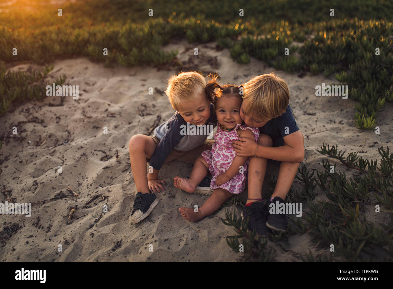 Siblings sitting together on sand hi-res stock photography and images ...
