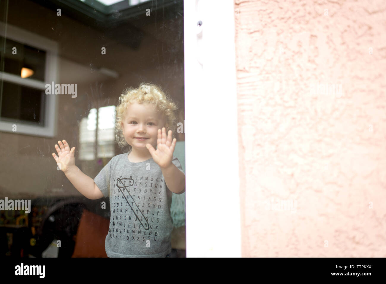 Portrait of cute boy standing at home seen through window Stock Photo ...
