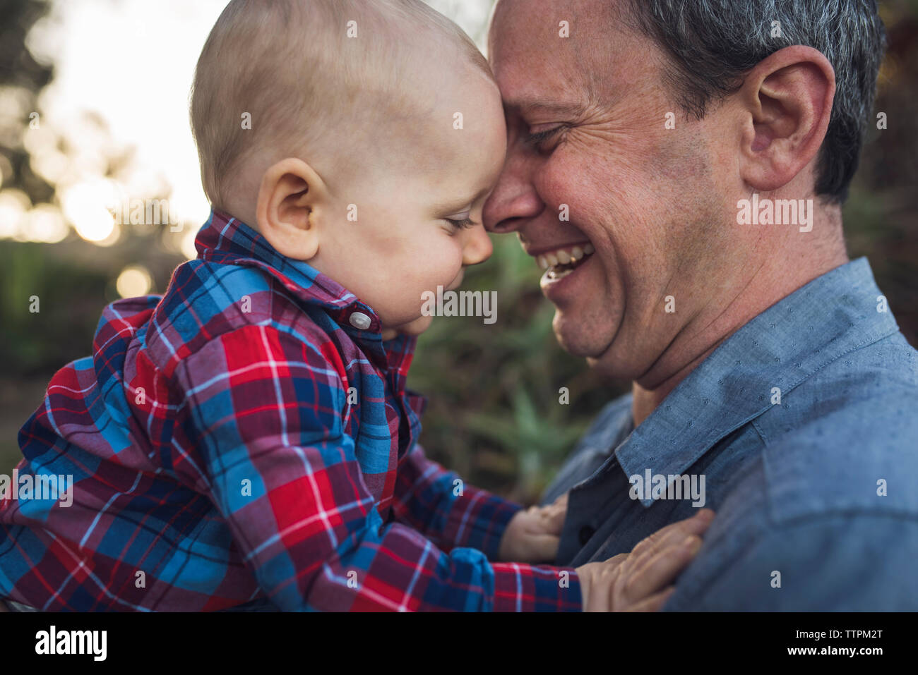 Side view of smiling father and son at park Stock Photo - Alamy