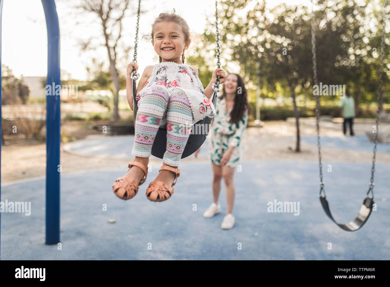 Happy mother pushing cute daughter swinging at playground Stock Photo - Alamy