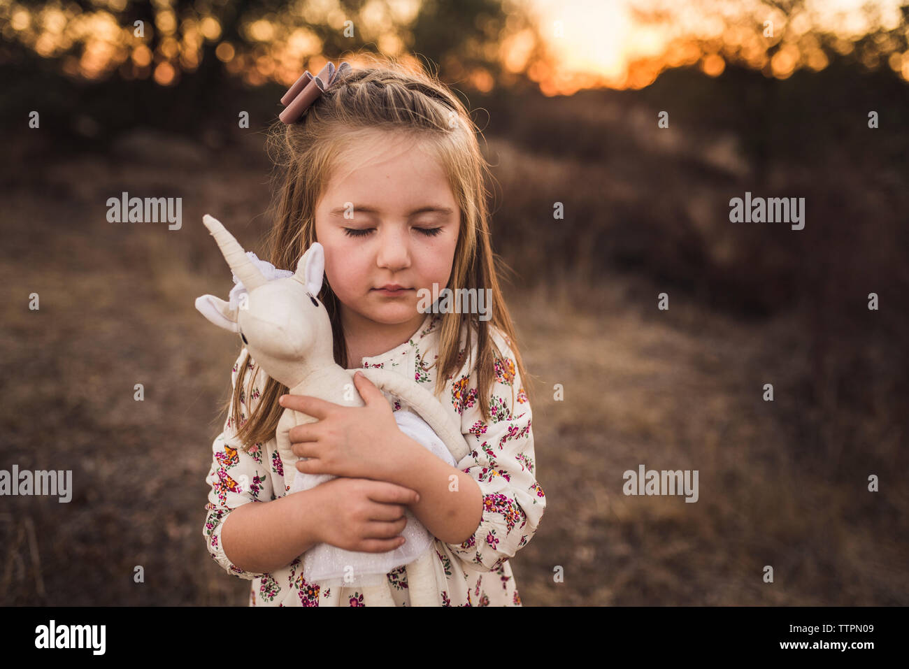 Portrait of young girl holding stuffed animal toy with eyes closed ...